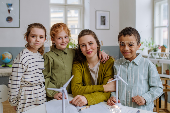 Young teacher with model of wind turbine learning pupils about wind ...
