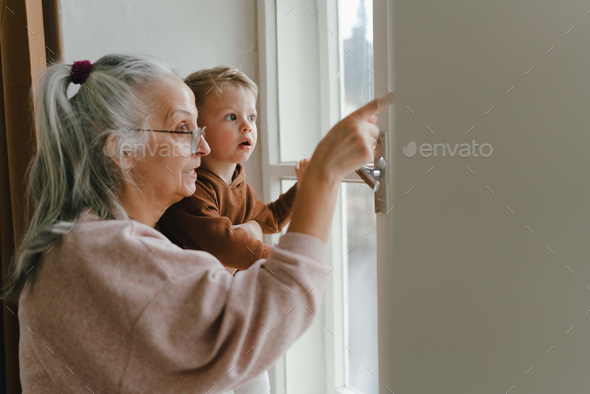 Grandmother with her little grandson looking out of the window. Stock ...