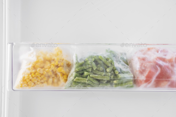 Frozen vegetables in plastic bags in freezer close-up, top view. Stock ...