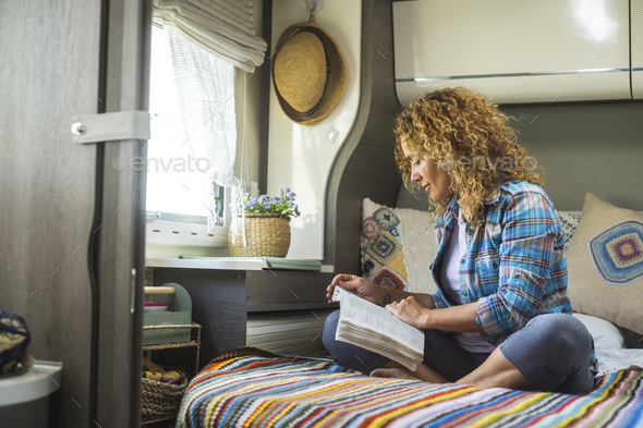 One woman reading a book sitting inside a modern camper van motorhome ...
