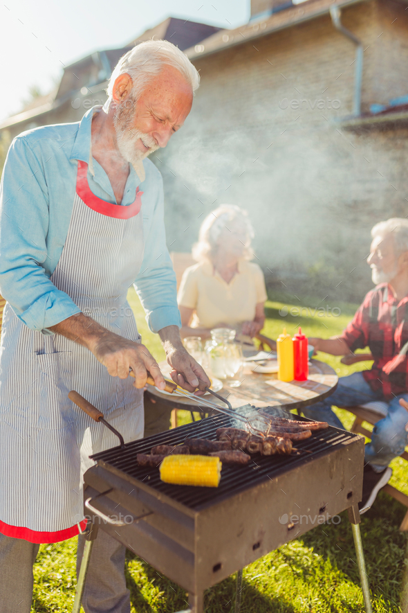 Senior neighbors making barbecue in the backyard Stock Photo by ...