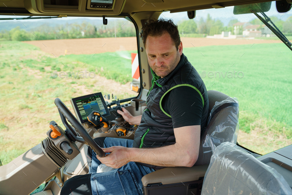 A photograph of a farmer using a tractor and other farming equipment to ...