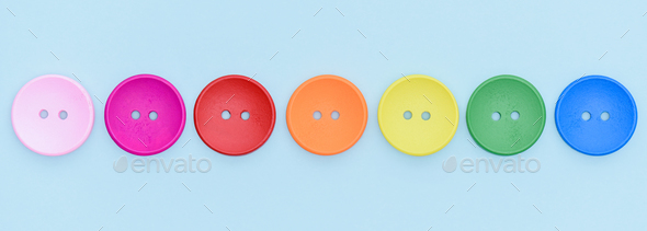 Colored wooden rainbow sewing buttons in a row on a light blue ...