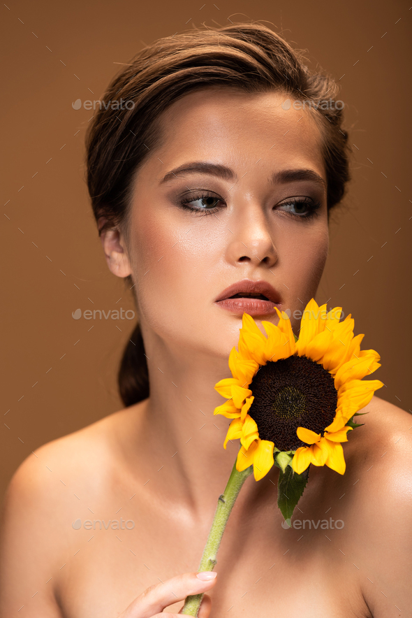 beautiful young naked woman with yellow sunflower looking away isolated on brown Stock Photo by ...