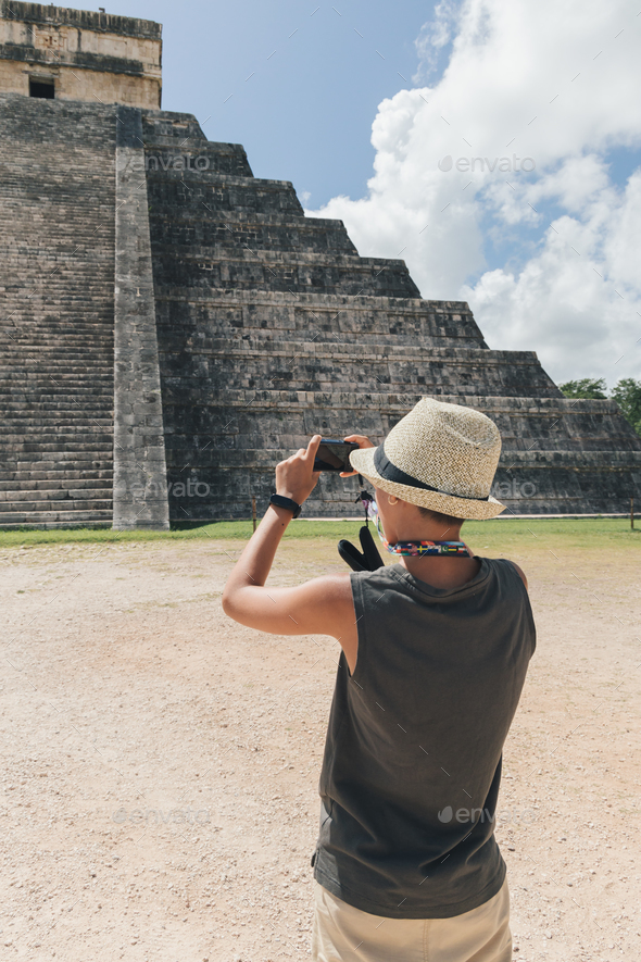 Teenage girl with hat taking a picture of the pyramid of Kukulcan in ...