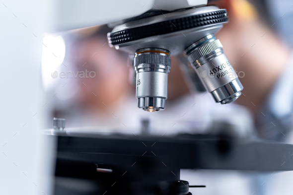 Scientist analyzing microscope slide at laboratory. Young woman ...