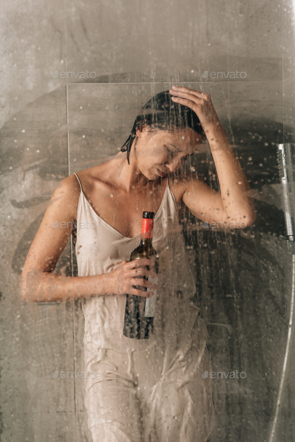 depressed woman in shower holding wine bottle and crying at home Stock ...
