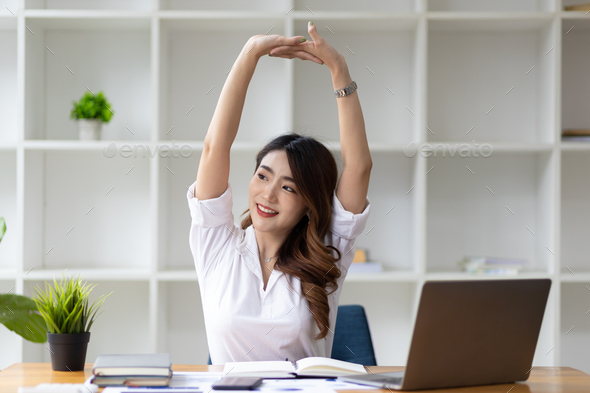 Business woman working in an office stretches to relax from work during ...