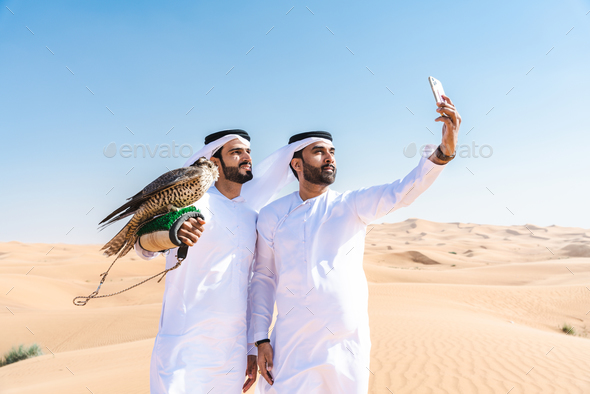 Two middle-eastern emirati men wearing arab kandura holding falcon in ...