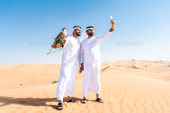 Two middle-eastern emirati men wearing arab kandura holding falcon in ...