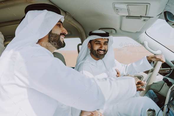 Two middle-eastern emirati men wearing arab kandura driving car in the ...