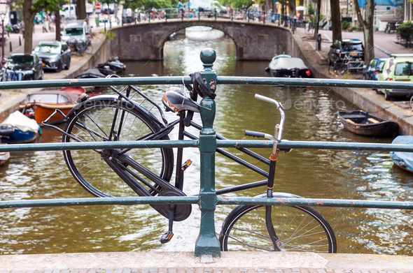 Bicycle hanging on bridge railing in Amsterdam Stock Photo by Cebas
