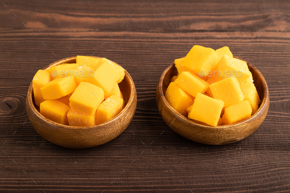 Dried mango cubes in wooden bowls on brown wooden, side view. Stock ...