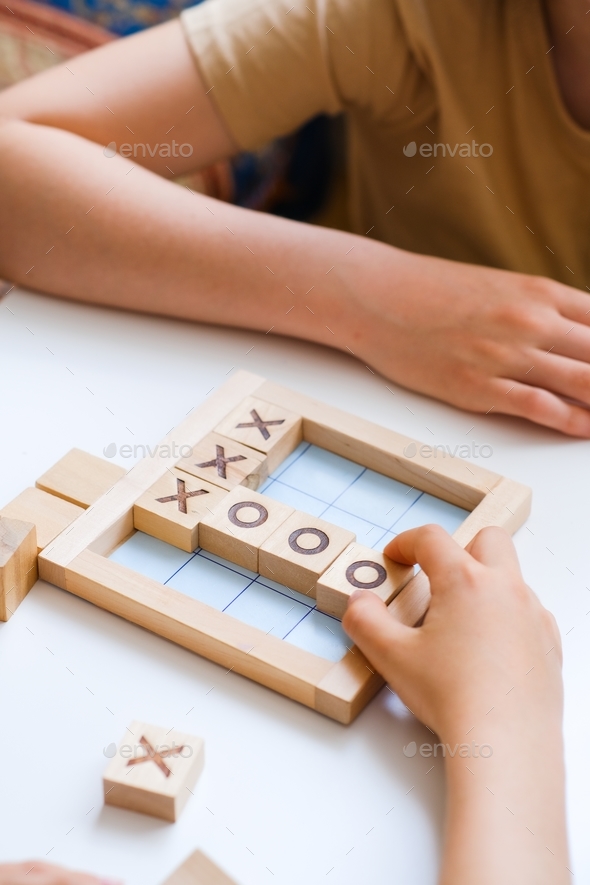 Two children are playing board games. Tic-tac-toe and dominoes. Cozy ...