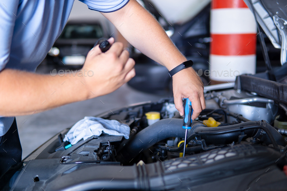 Auto mechanic working and repairing a car engine in a garage with a ...
