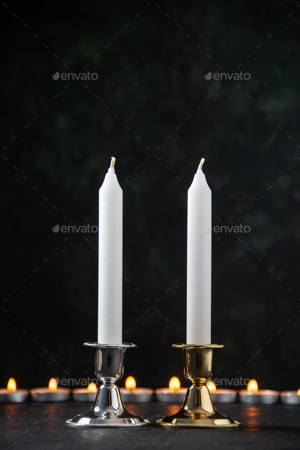 front view of burning candles as memory for fallen on dark surface ...