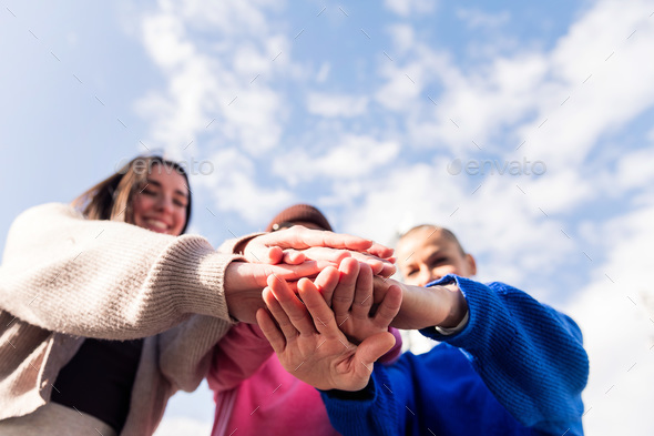 three happy friends holding hands in unity Stock Photo by Raul_Mellado