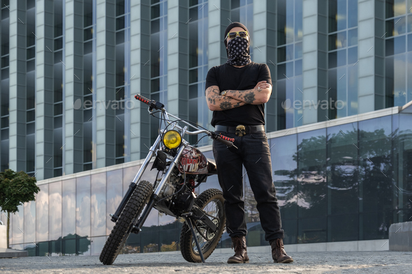 Confident rocker biker dressed in black clothes with motorcycle Stock ...