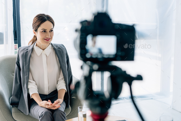 selective focus of attractive journalist in formal wear smiling in ...