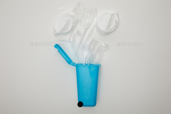 top view of blue recycle bin with crumpled plastic cups, forks and ...