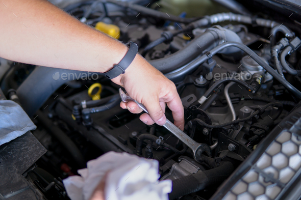 Auto mechanic working repairing a car engine with an open-end spanner ...