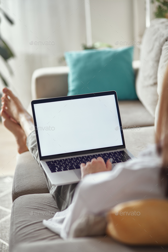 Mockup white screen laptop woman using computer lying on sofa at home ...