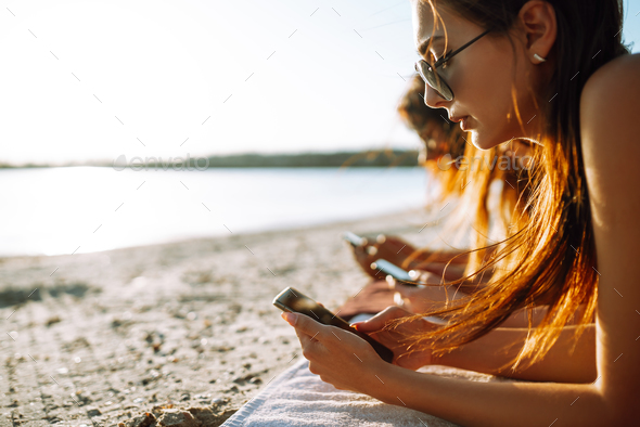 Three beautiful girls using mobile smart phone at the beach. Girls ...