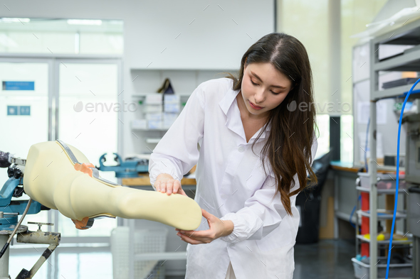Female technician assembling and fixing parts of modern prosthetic leg ...