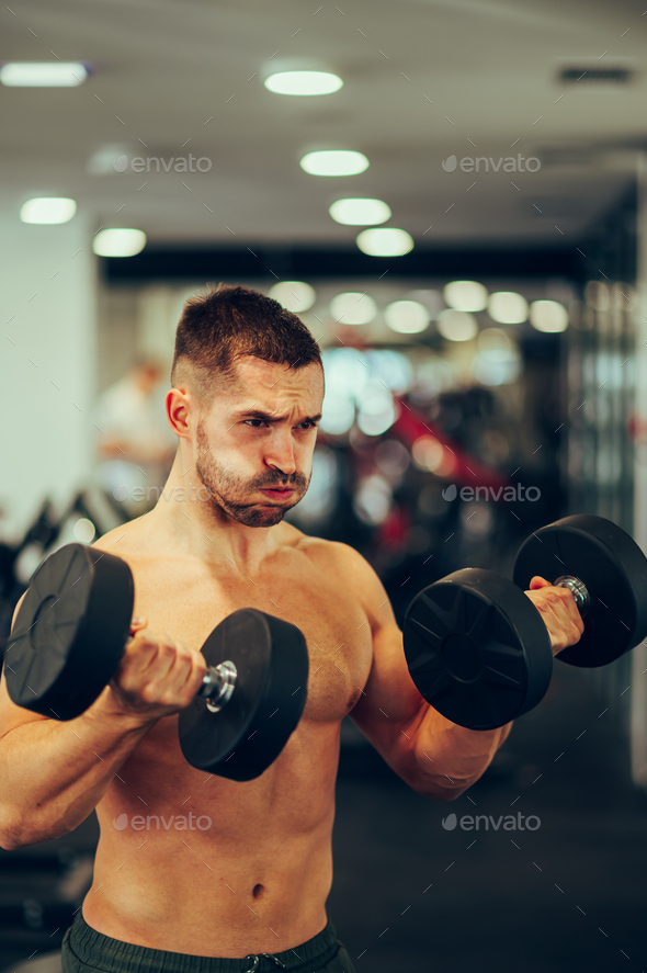 A strong muscular man in shape with big muscles is lifting heavy ...