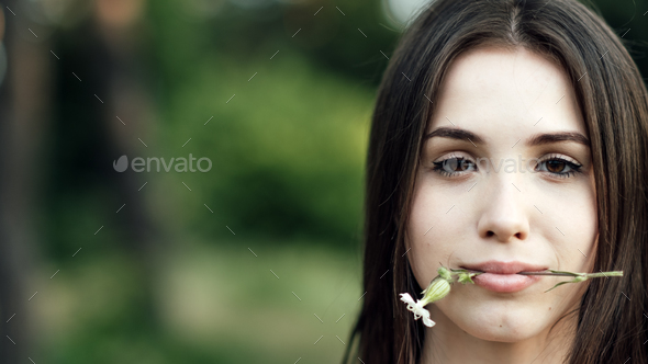 Beautiful young woman covering eye with daisy flower on nature ...