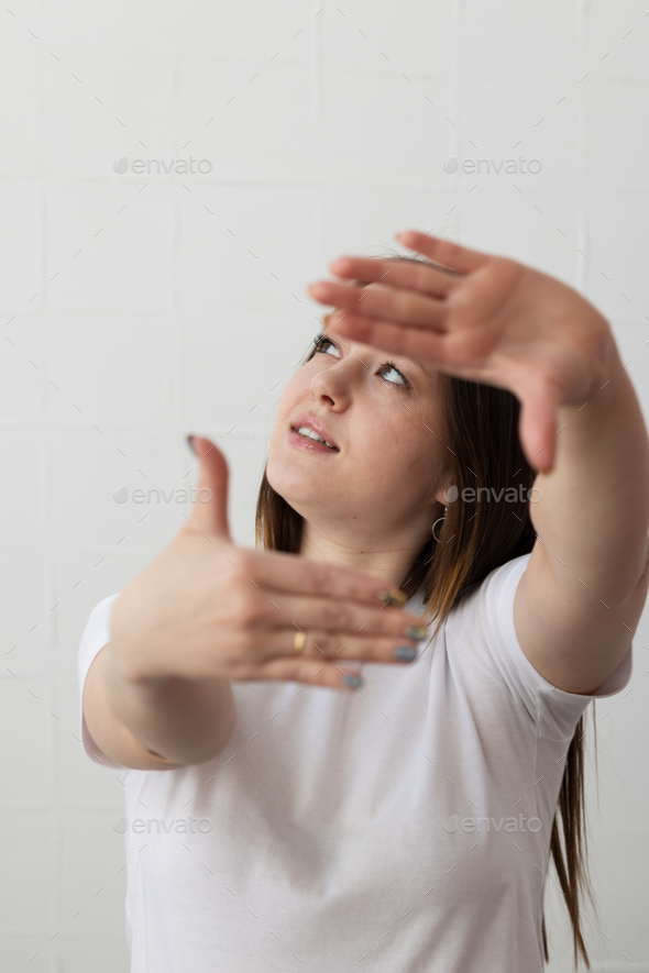Young cute girl posing and looking at the camera through a frame made ...
