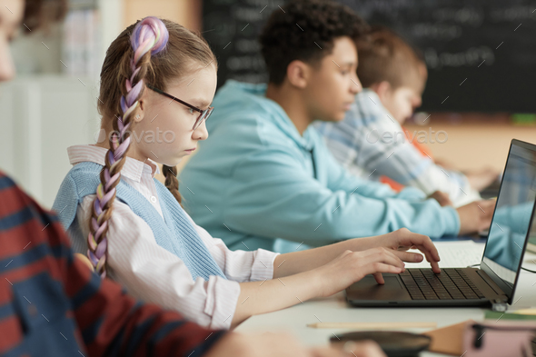 School children using computers in row Stock Photo by seventyfourimages