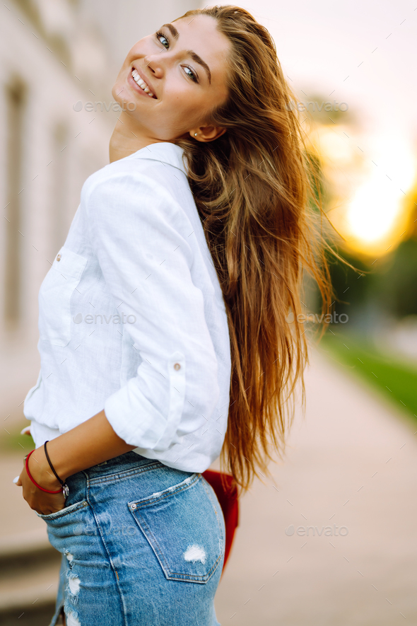 Portrait of young beautiful girl smiling looking camera. Beautiful girl posing in the park ...