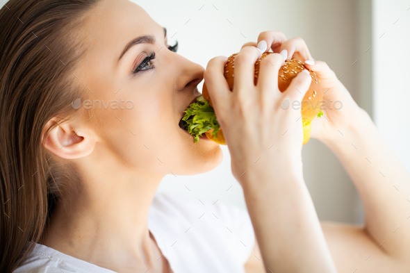Young woman eating hamburger woman eating junk food Stock Photo by maksymiv