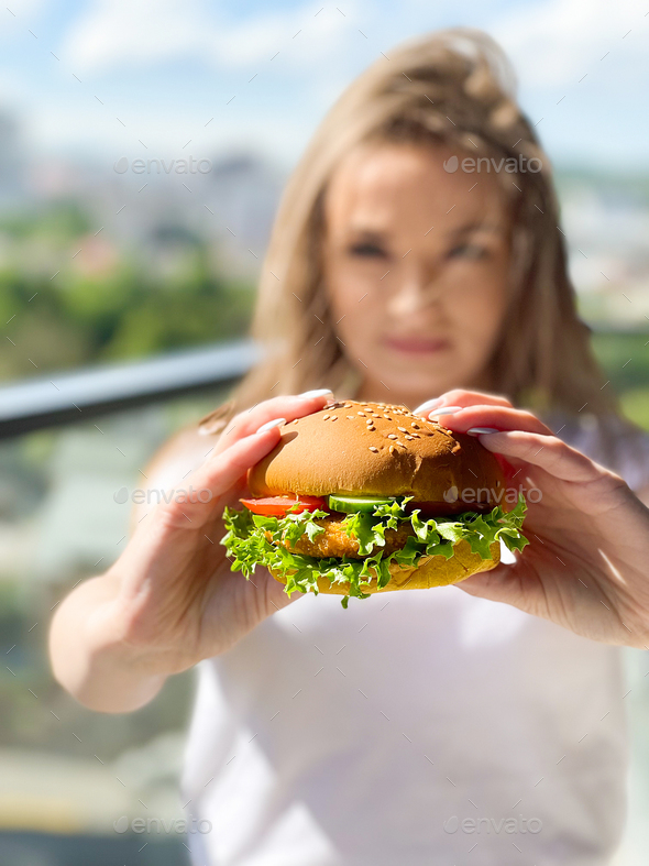 Young woman eating hamburger woman eating junk food Stock Photo by maksymiv