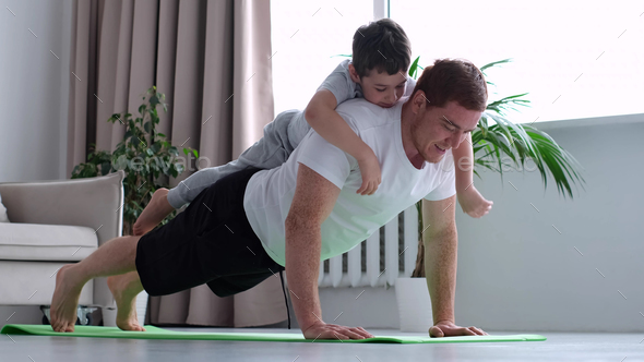 happy father doing push up exercise with son on back at gym. little boy ...