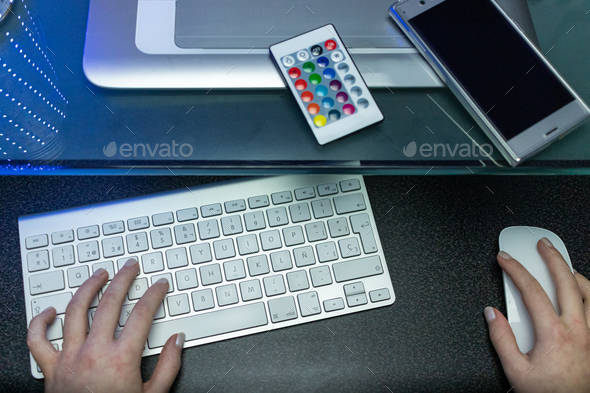 Person typing on the white keyboard and holding the mouse next to a ...