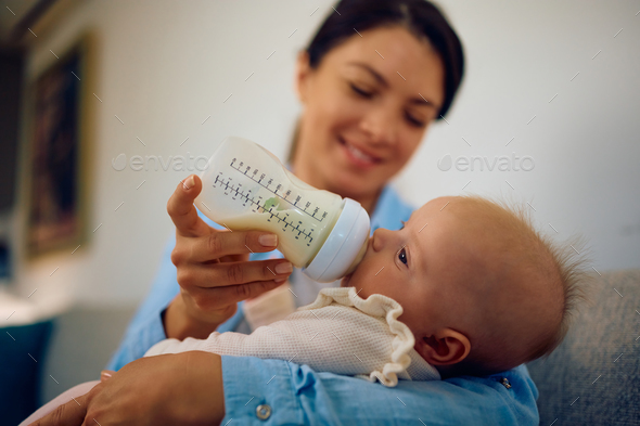 Baby girl being bottle fed by her mother at home. Stock Photo by ...