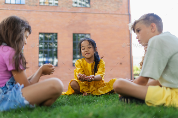 Happy kids playing and talking together in city park, during summer day ...