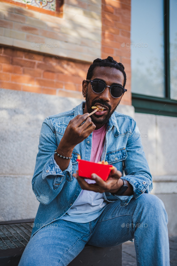 Man eating french fries with bacon and cheddar Stock Photo by pablorasero