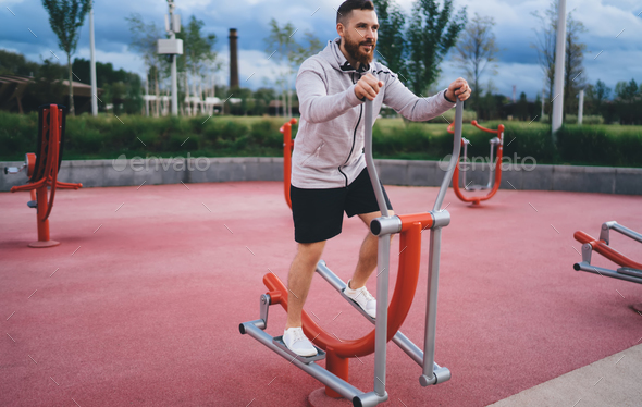 Young man doing exercises on step machine at park Stock Photo by GaudiLab