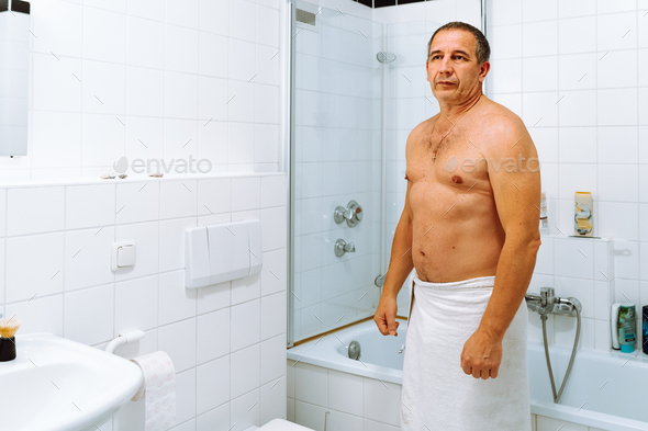 Portrait man after shower in bathroom with white tiled floor and walls ...