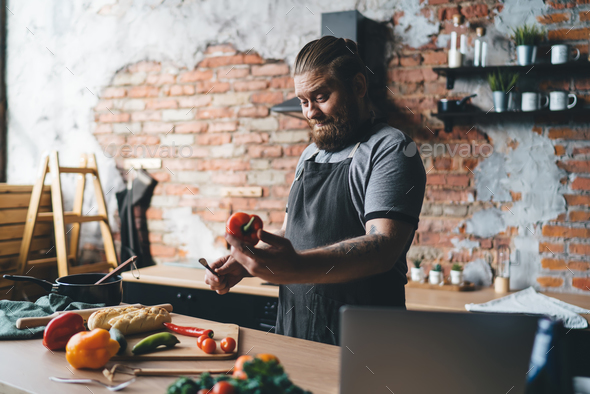 Positive chef making healthy food in rustic kitchen Stock Photo by GaudiLab
