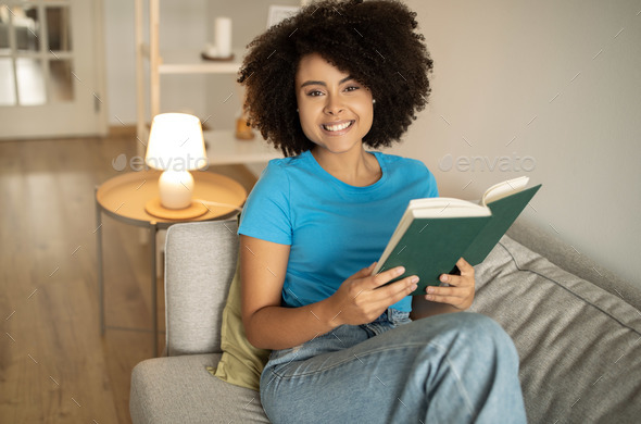 Relax at weekend alone. Positive millennial curly black lady reading ...