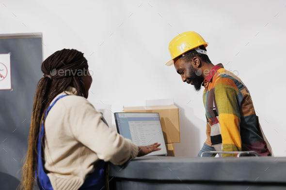 Warehouse colleagues chatting at counter while checking orders list ...
