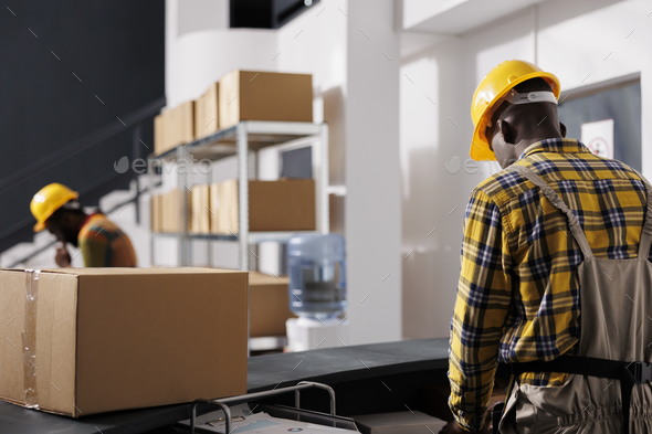 Delivery service worker standing at reception, managing parcel ...