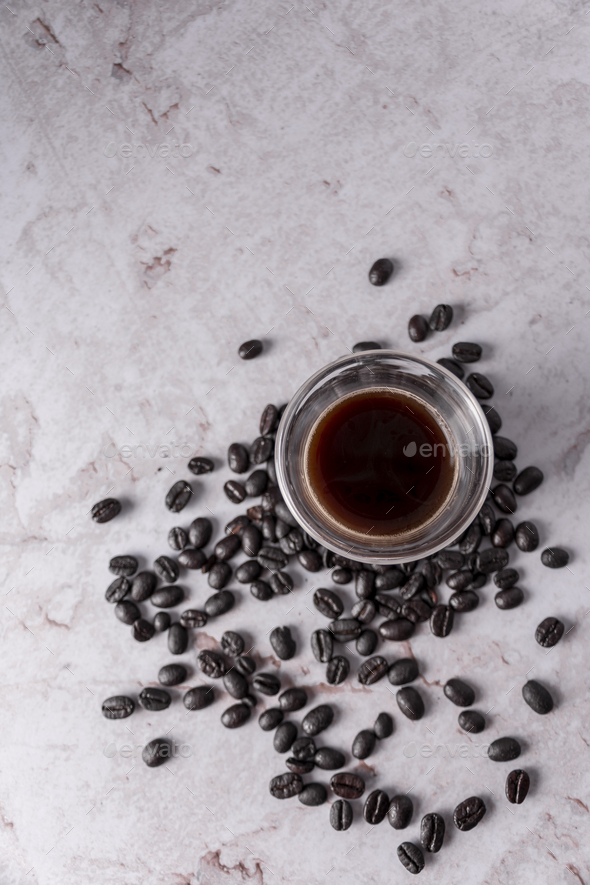 Vertical top view of black coffee with coffee beans on a marble surface ...
