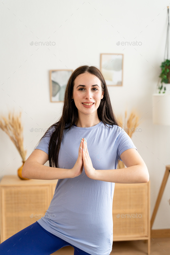 Woman doing tree pose at home. Stock Photo by TheAtticoStudioPhoto