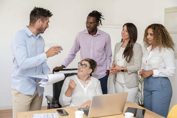 multicultural team gathered around their business leader in a ...