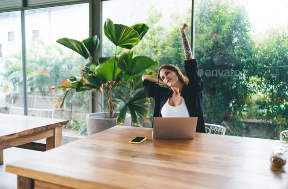 Positive woman stretching body while working remotely Stock Photo by ...